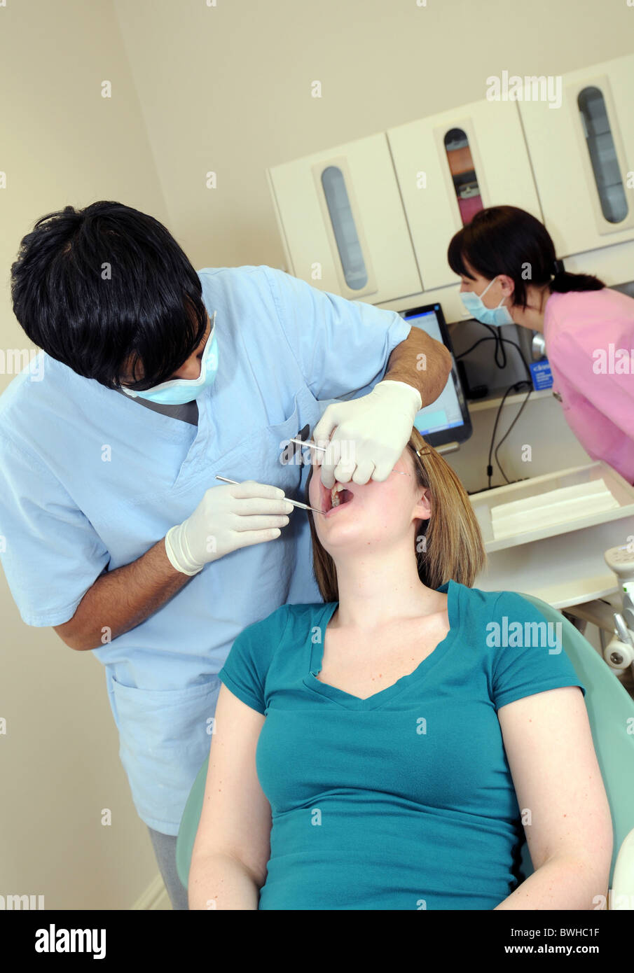Female patient at a dental surgery having a teeth check up by a male ...