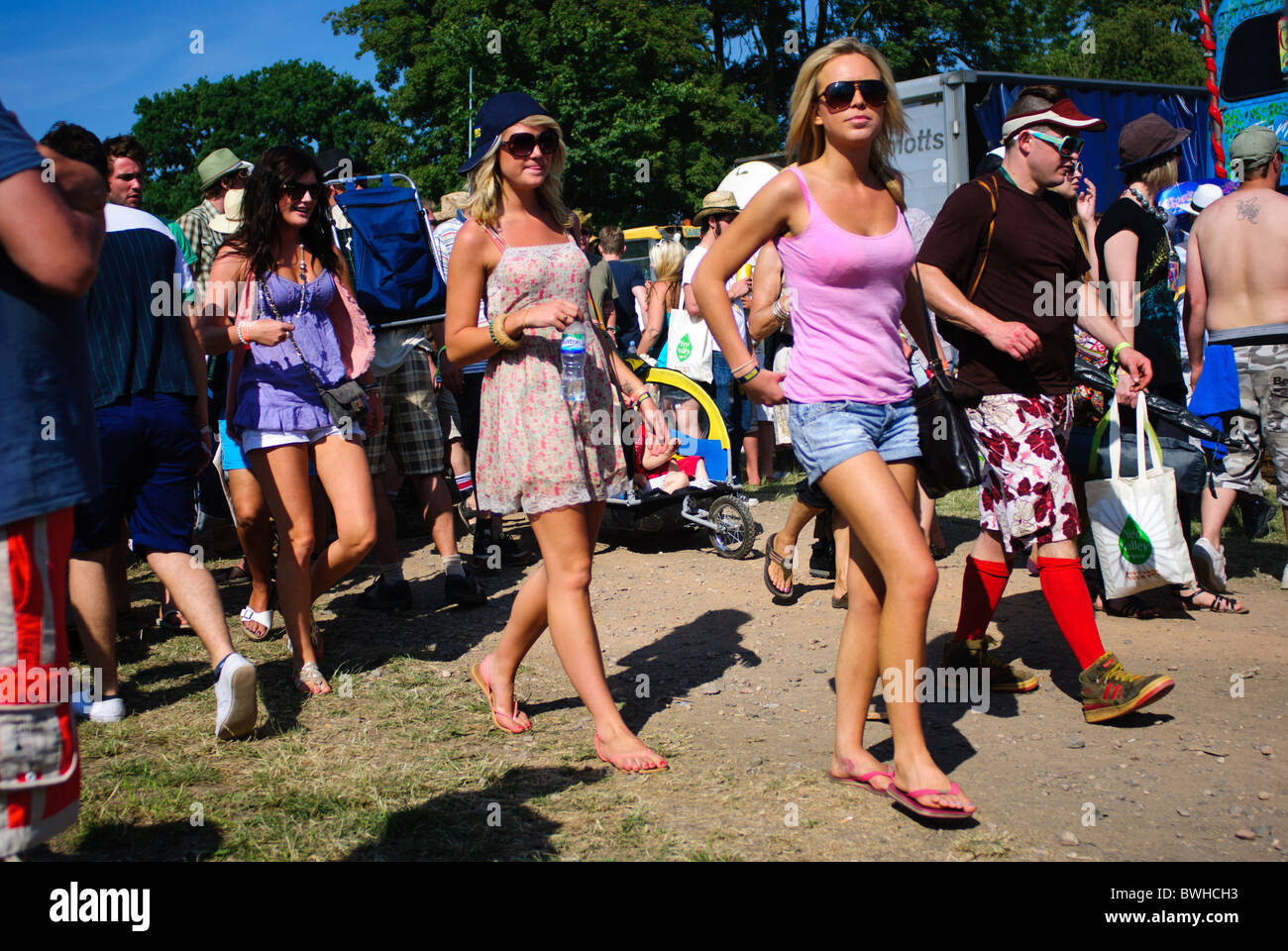 Crowds walking along the path on a hot summers day at Glastonbury ...