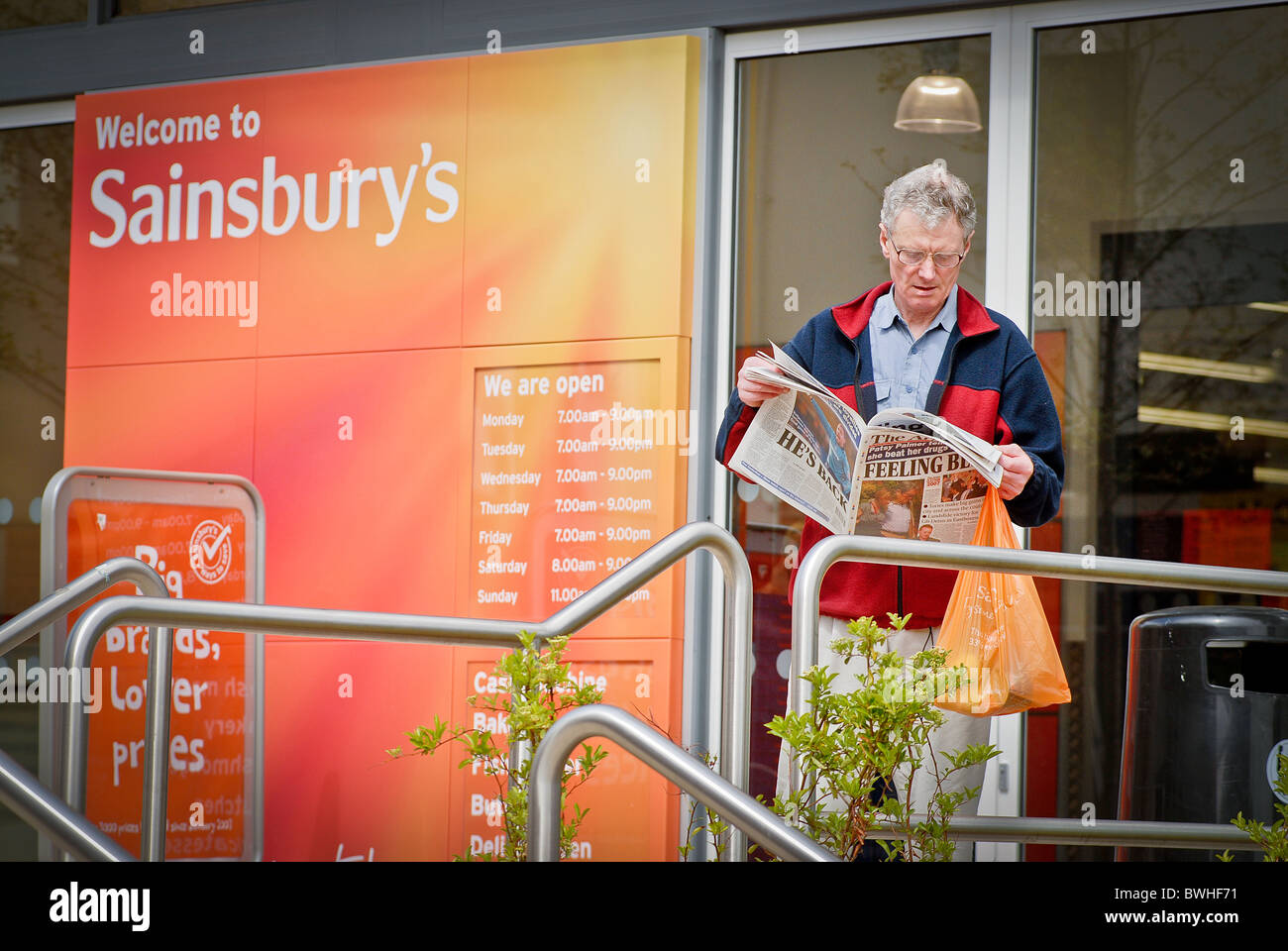 Man outside Sainsbury's Supermarket reading paper Stock Photo - Alamy