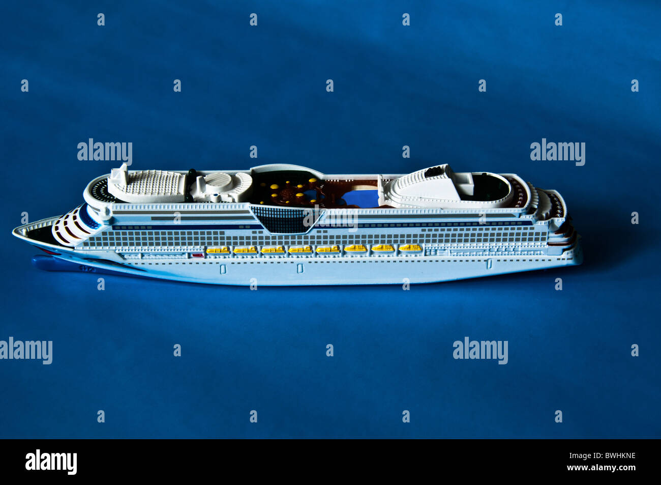 Miniature model of a cruise ship (childrens toy) on blue paperMiniature ...