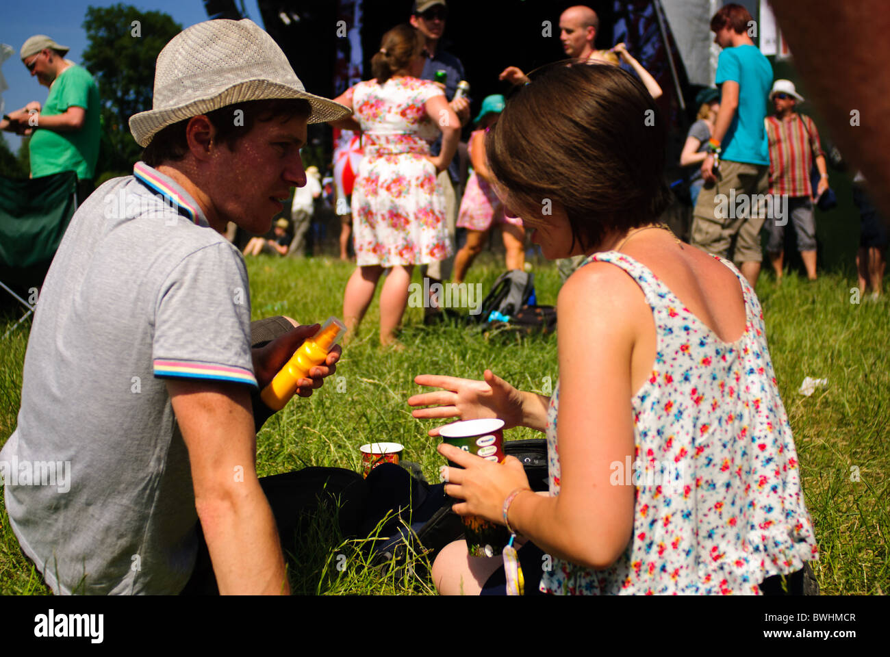 Young couple applying sunscreen and drinking alcohol in the heat at ...