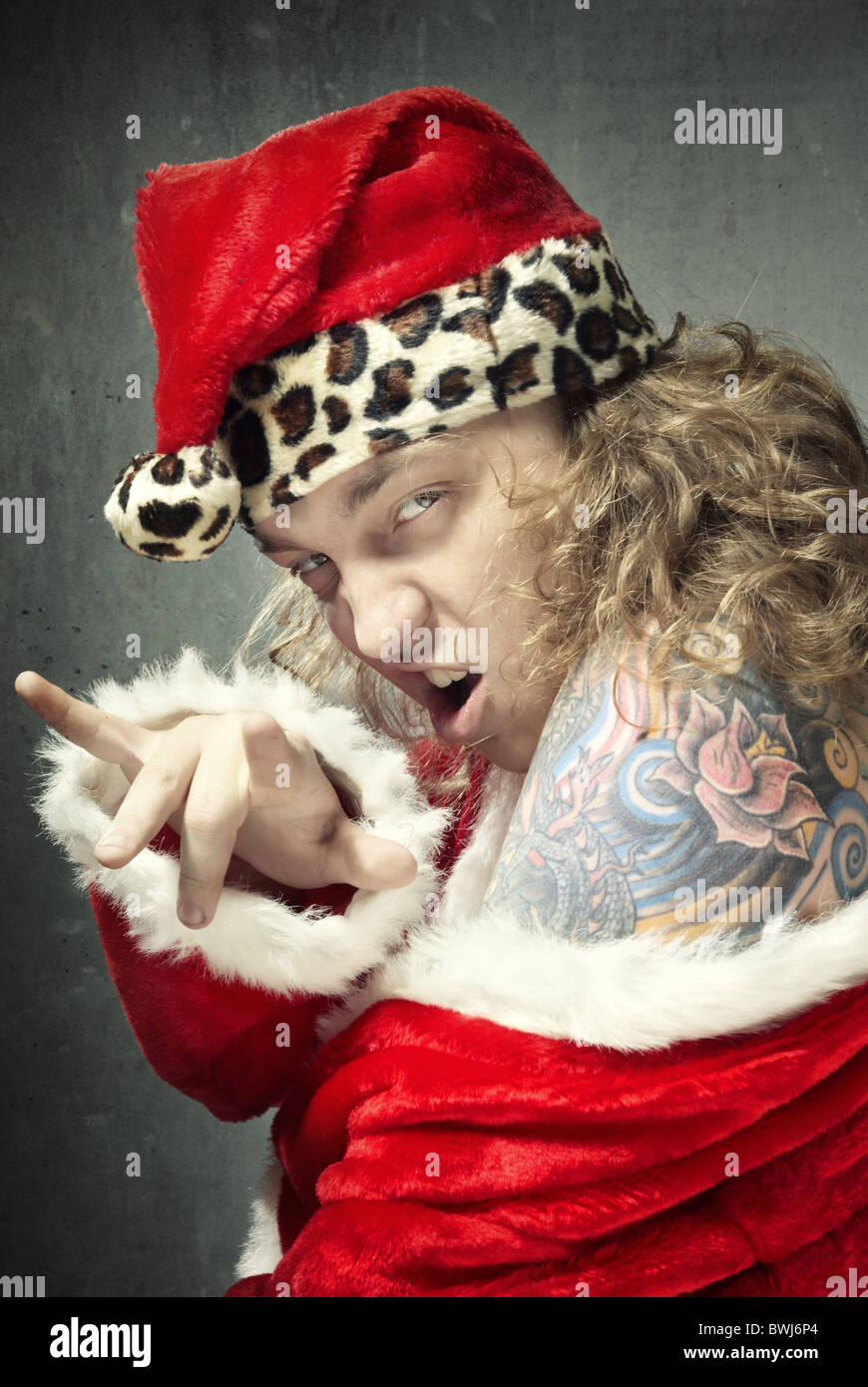 Stylish man with tattoo gesturing in the red furry Santa Claus costume ...