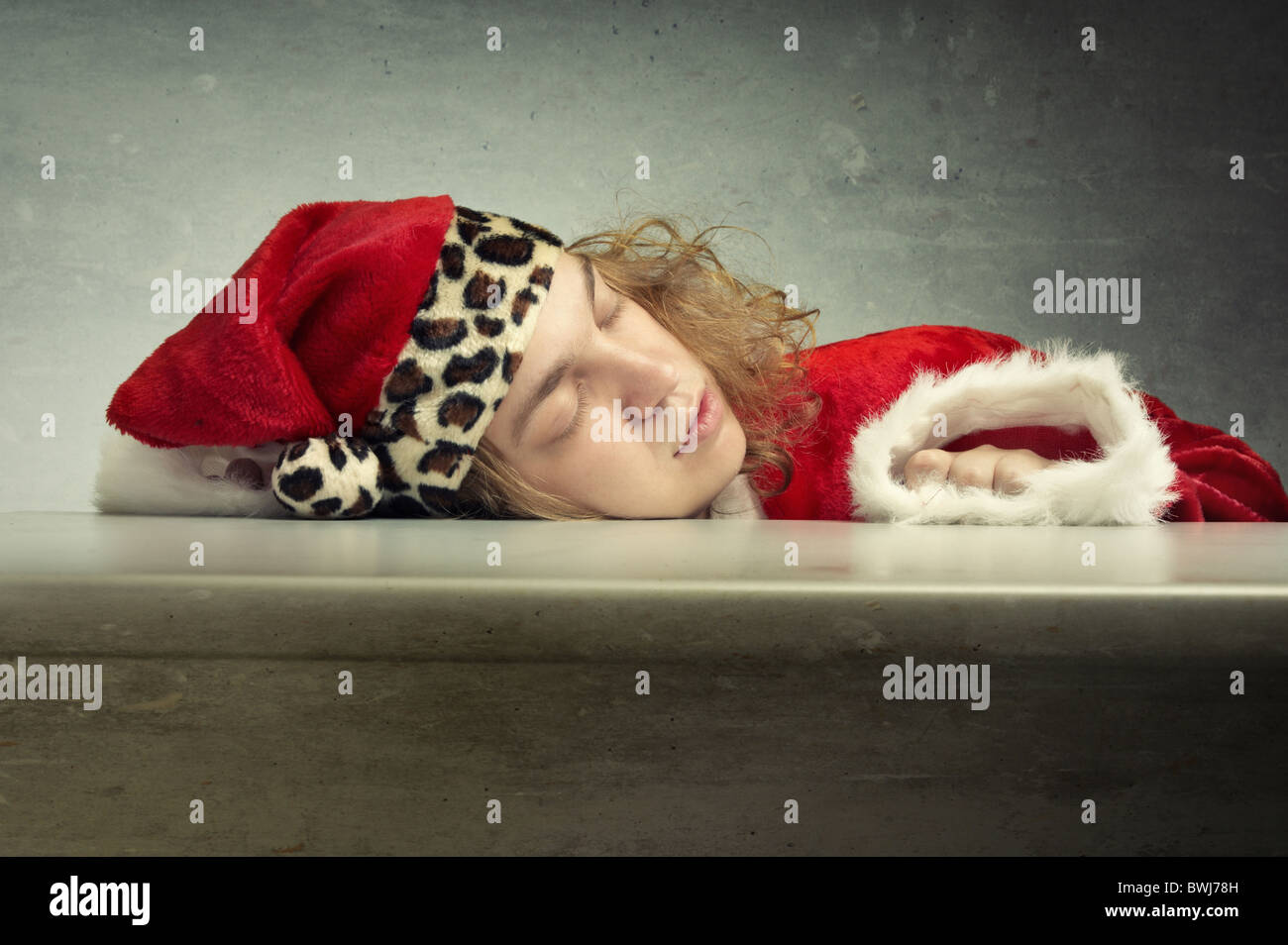 Young man in the red furry Santa Claus costume sleeping on the table in ...