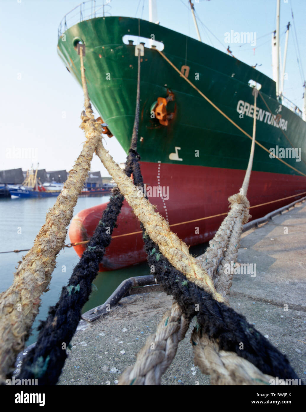 Green and red colored hull of a reefer / ship moored to the pier in ...