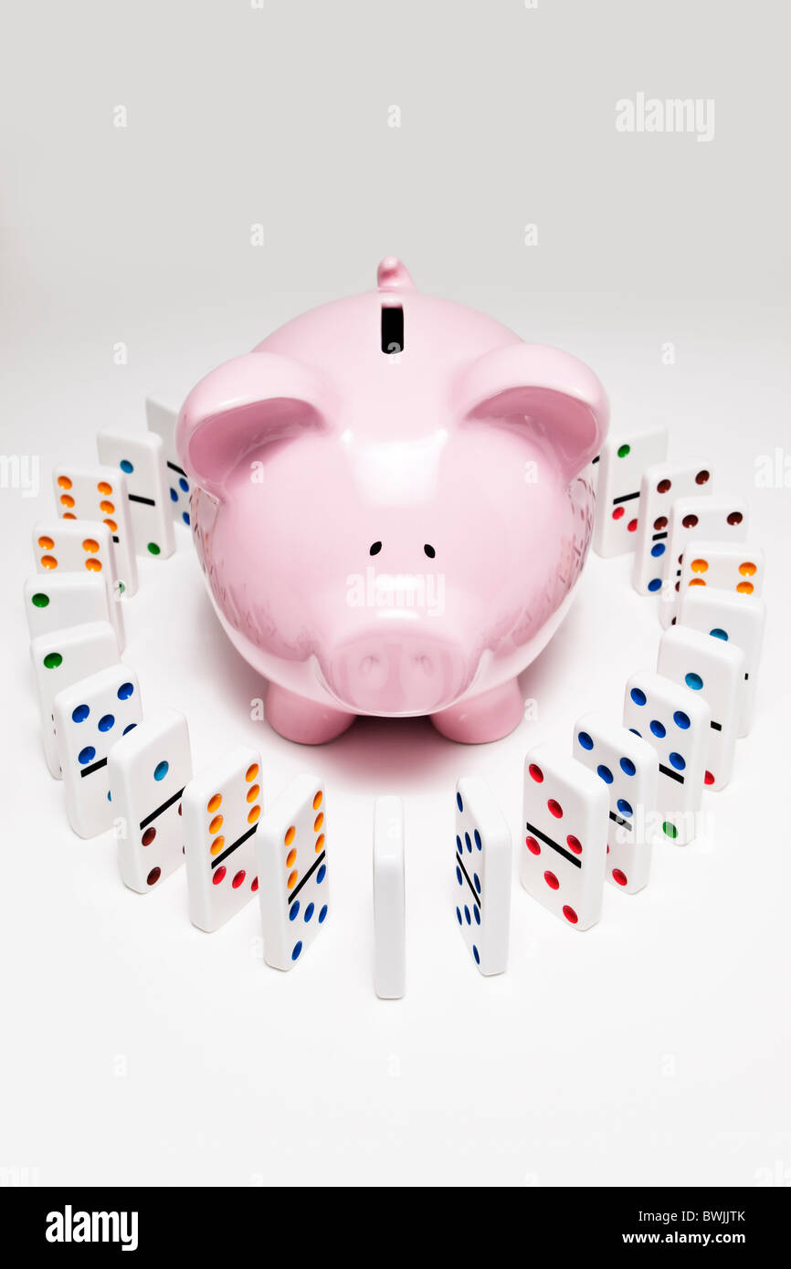 Piggy bank surrounded by dominoes Stock Photo - Alamy