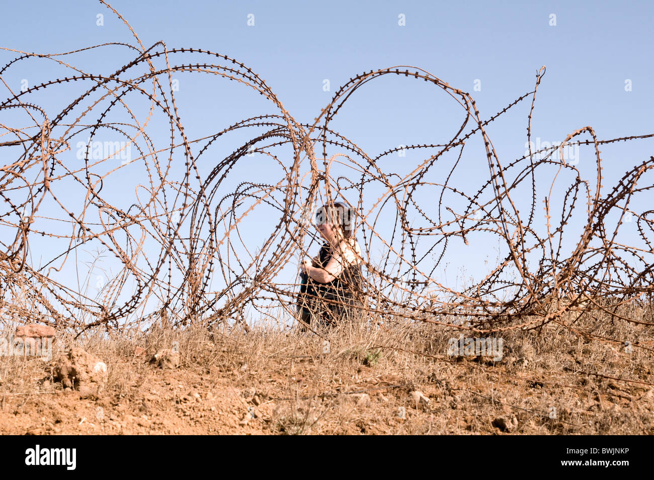 Woman, in her forties, confined by a Barbed wire fence Stock Photo - Alamy