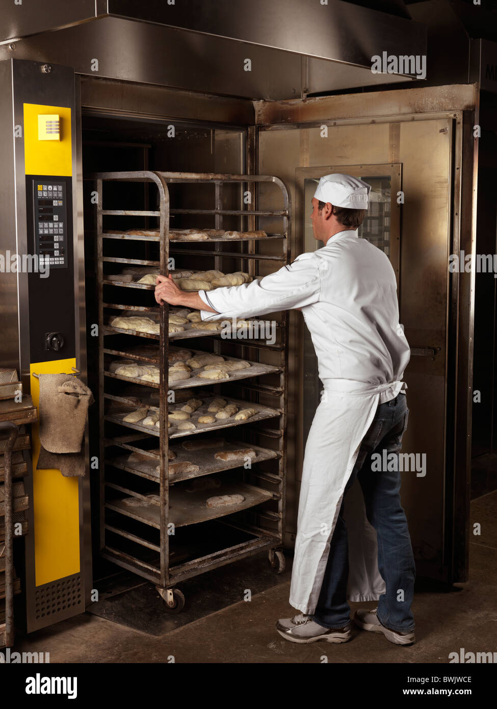 Baker rolling in a rack trolley with buns in a bakery oven Stock Photo ...