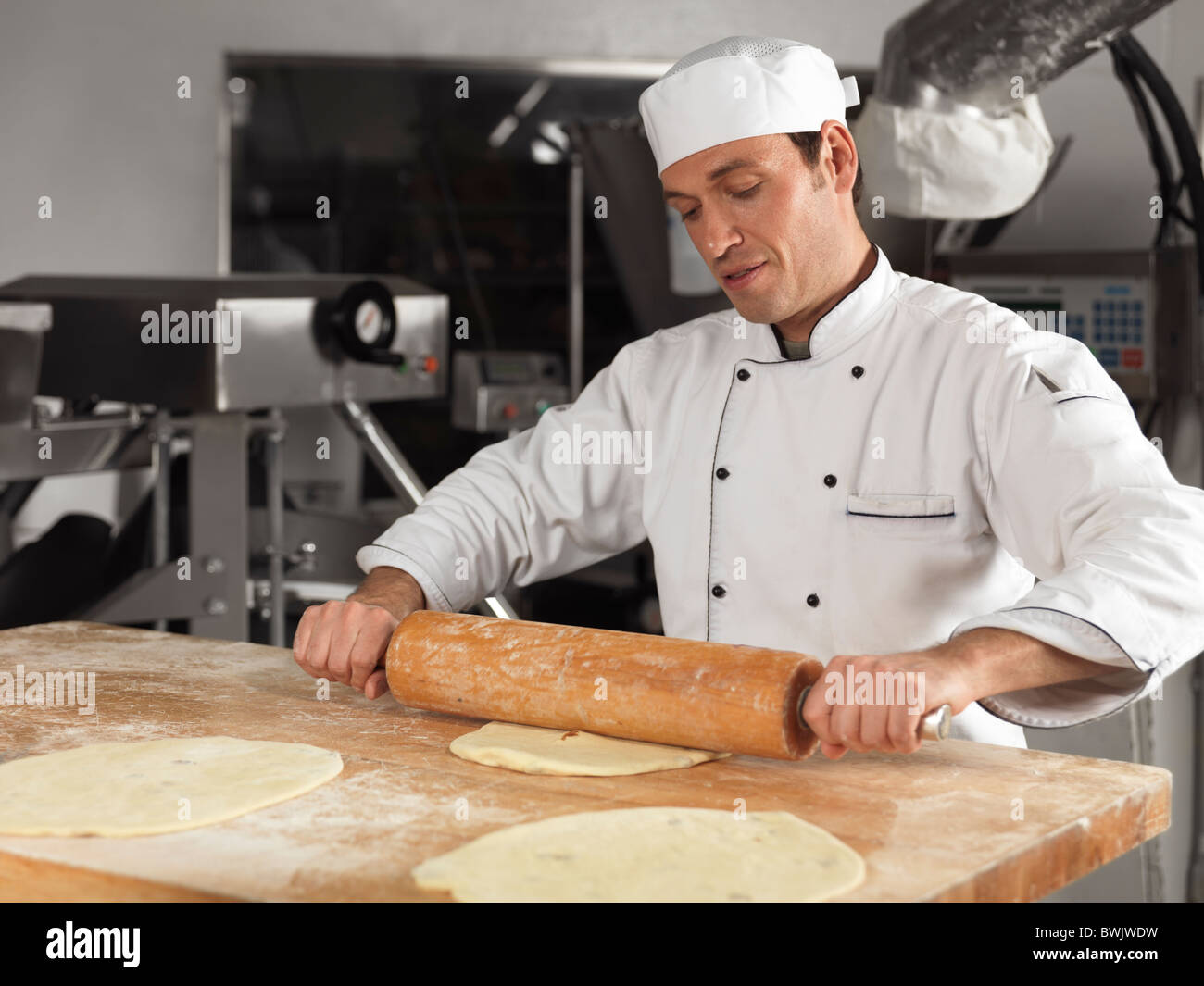 Baker rolling out dough with a rolling pin in a bakery Stock Photo - Alamy