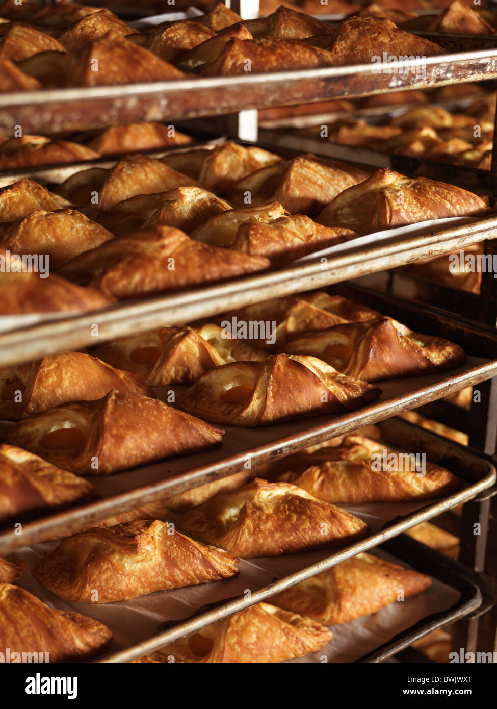Freshly baked pastries on baking trays in bakery rack trolleys Stock ...