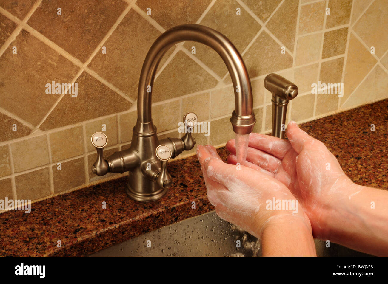 Soapy hand washing under flowing water out of a kitchen faucet Stock ...