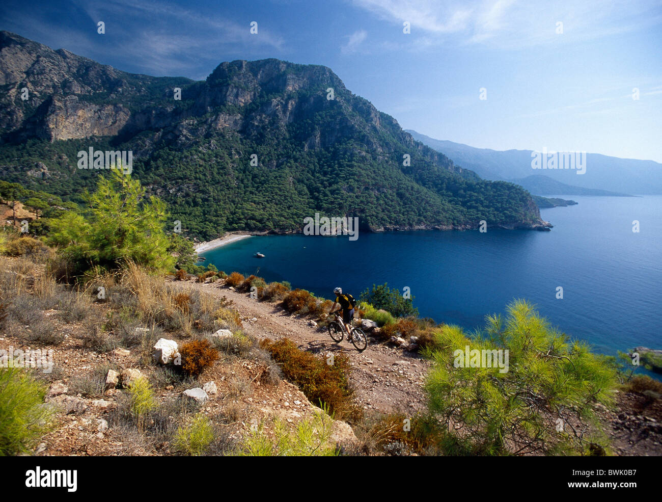 Mountain biker in front of Kabak Beach in a bay, Lycian coast, Turkey ...