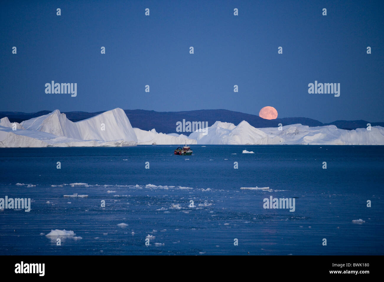 Full moon rising over icebergs from Ilulissat Kangerlua Icefjord at ...