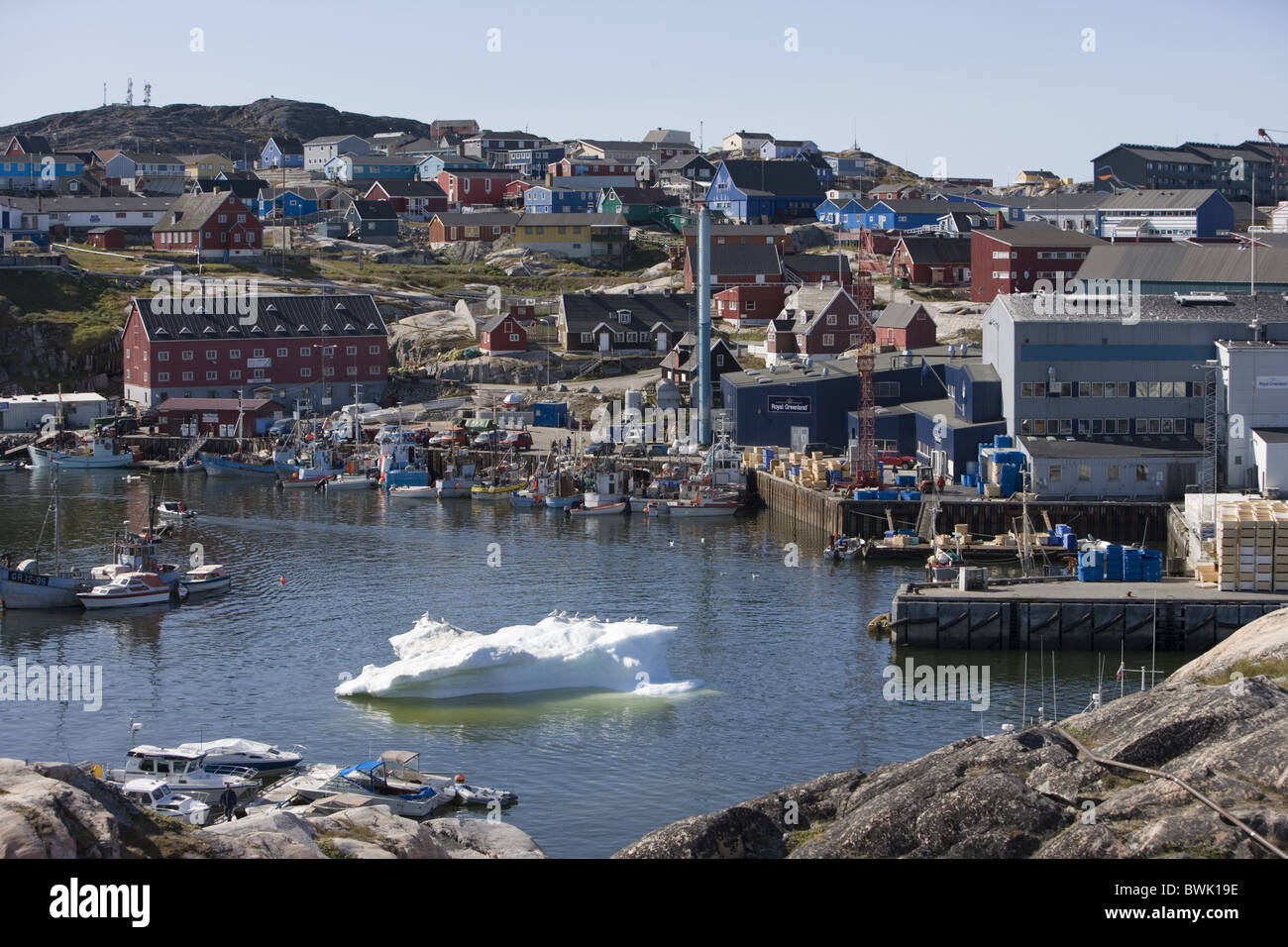 Iceberg at harbour with fishing boats and Royal Greenland Seafood ...