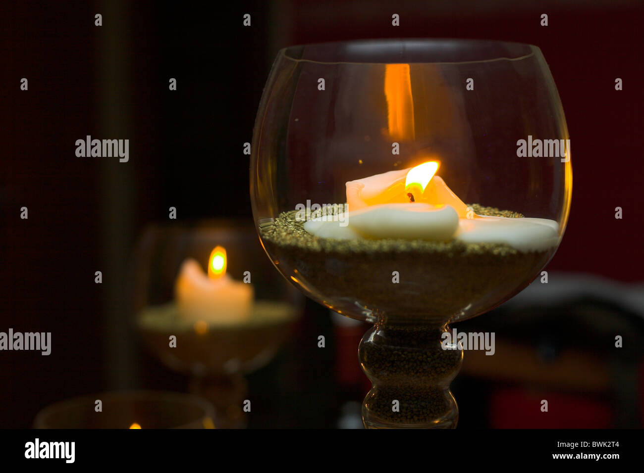 Large yellow white candle almost done burning, standing in a glass vase ...