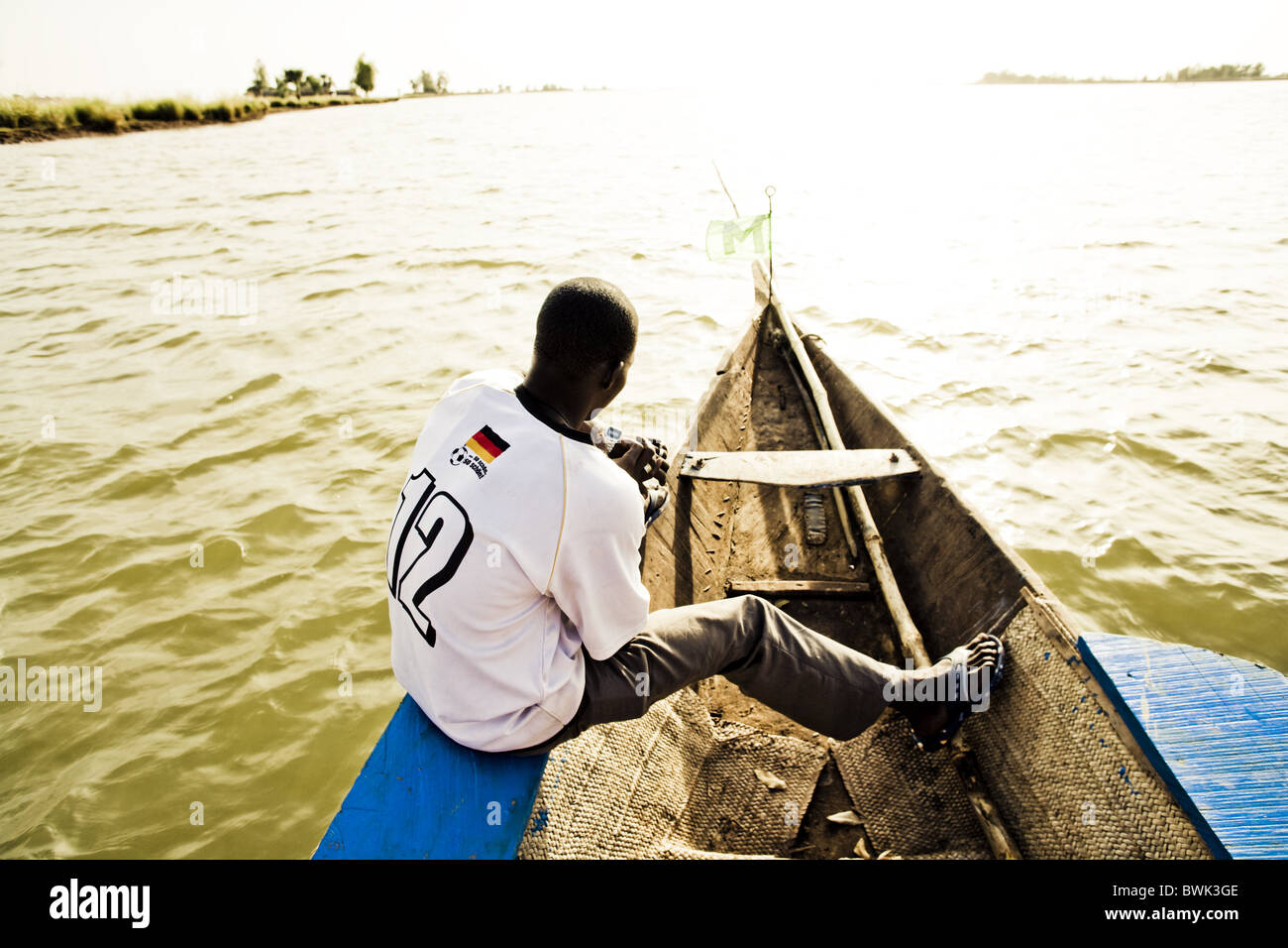 African man with german football shirt on a boat on the river Niger ...
