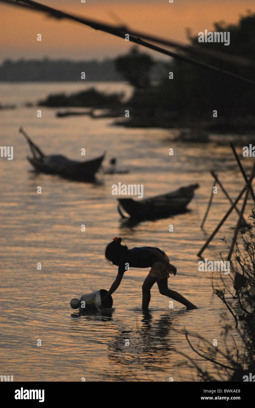 Girl getting water from the river Mekong at sunrise, Champasak ...