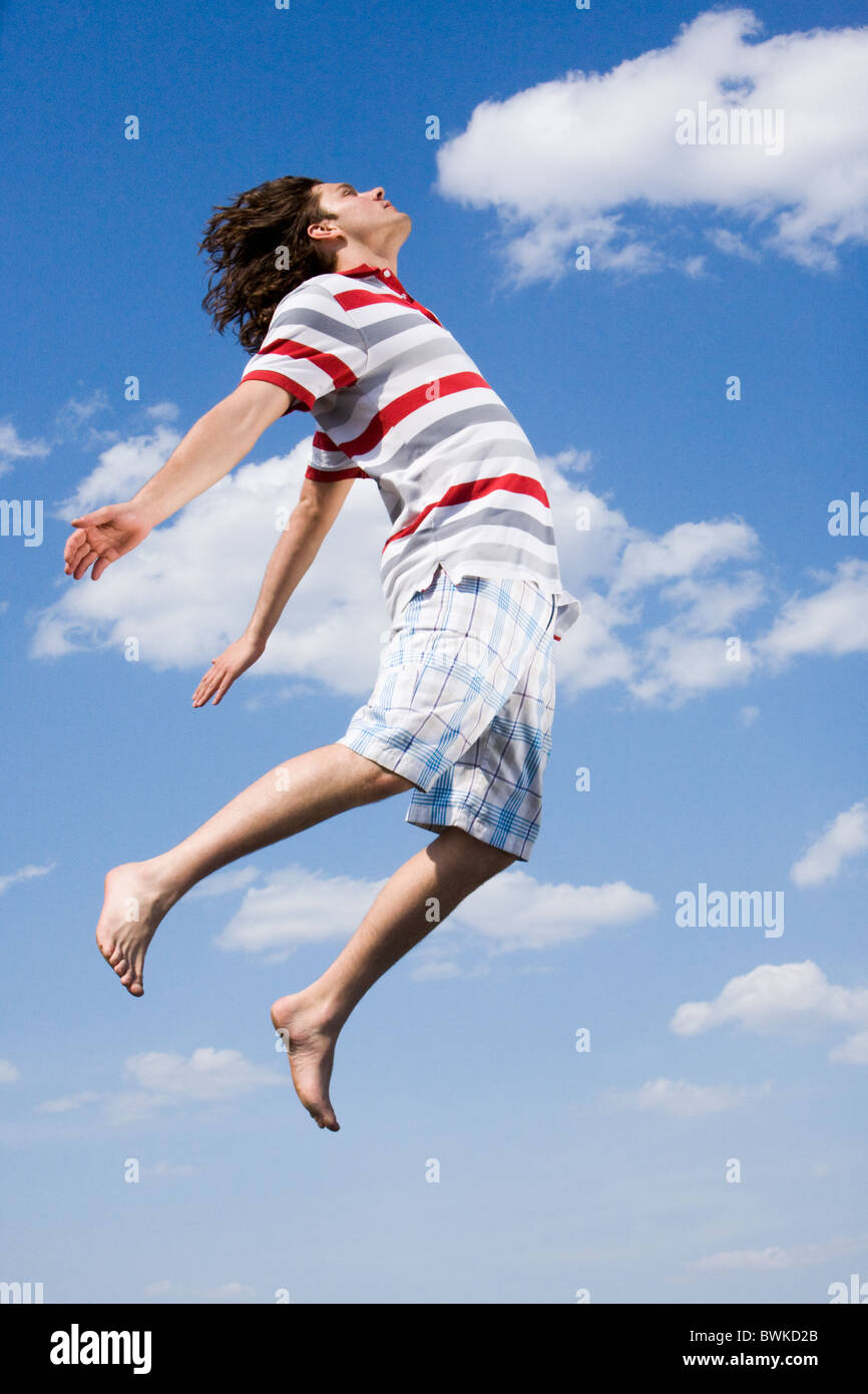 Portrait of energetic man jumping high against bright blue sky Stock ...