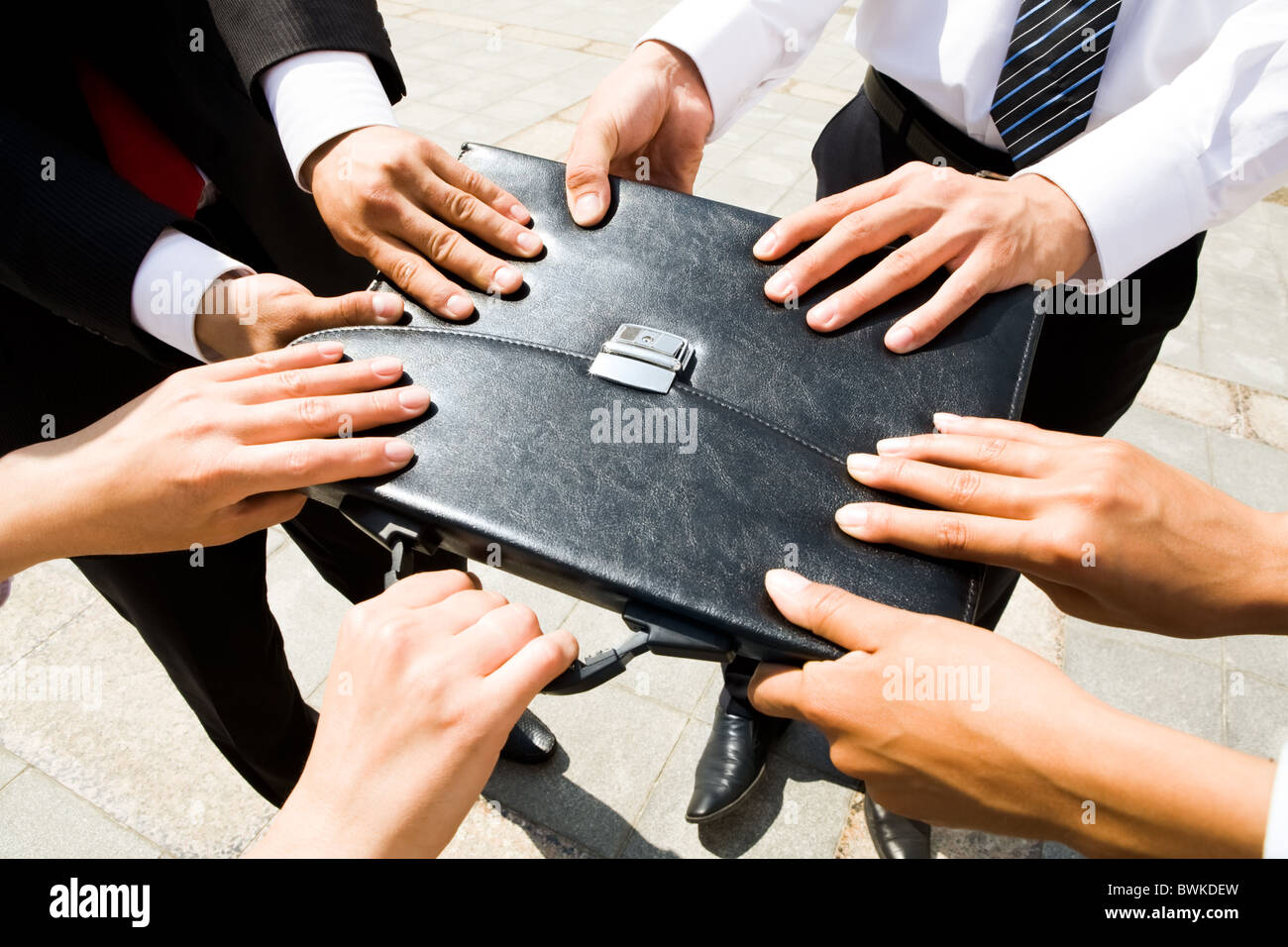Close-up of people hands holding black leather briefcase simultaneously ...
