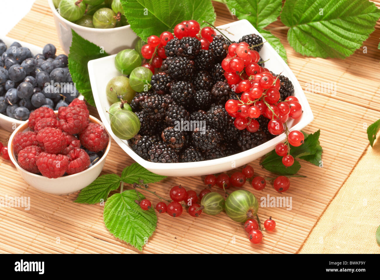 Berries in plates, on a table, among green leaves Stock Photo - Alamy