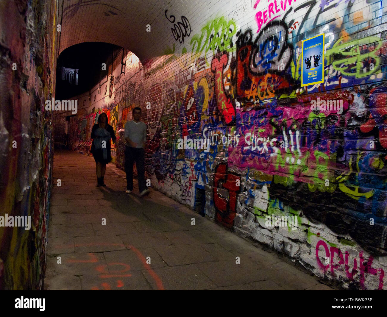 Two pedestrians walk past graffiti in "graffiti alley" in Gent, Belgium ...