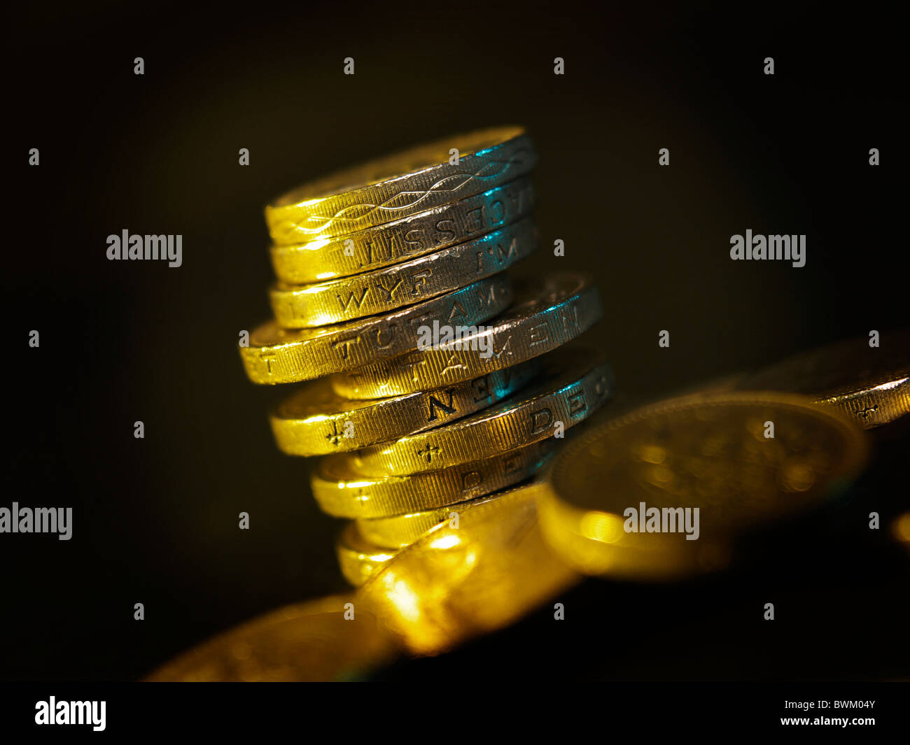 a stack of British pound coins with soft lighting stood up amongst ...