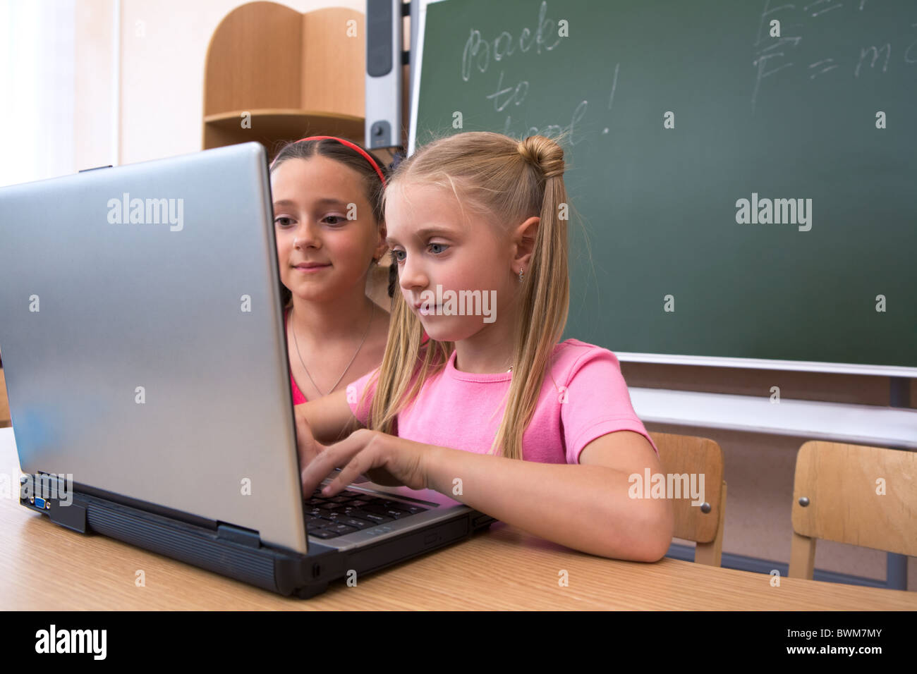 Portrait of two schoolgirls looking at the laptop during lesson Stock ...