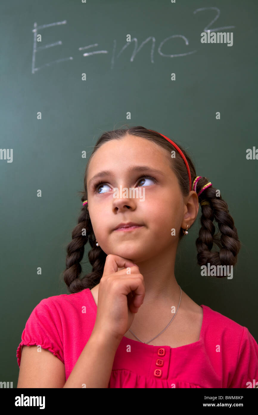 Photo of smart schoolgirl by the blackboard with pensive expression ...