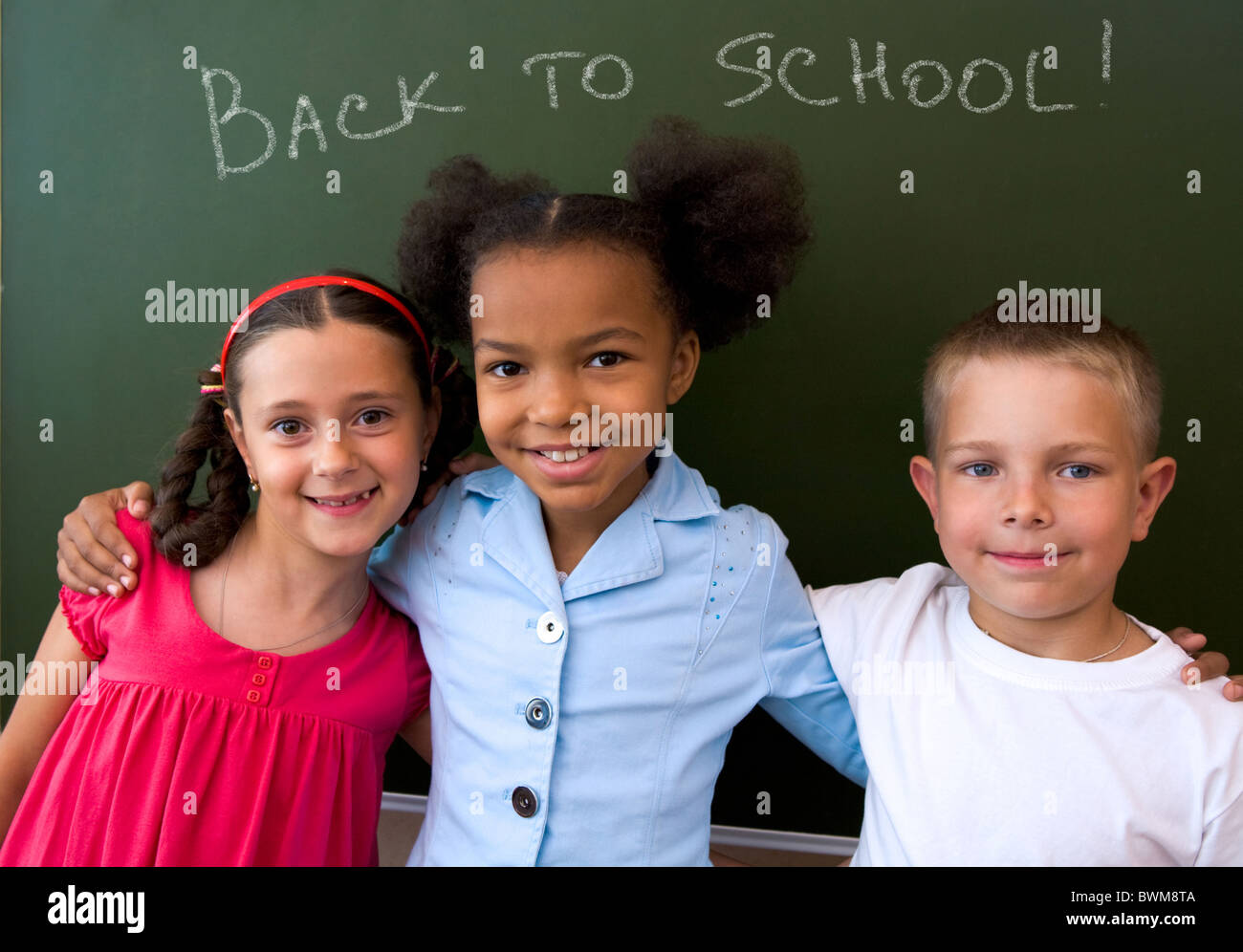 Image of clever schoolchildren standing by blackboard and looking at ...