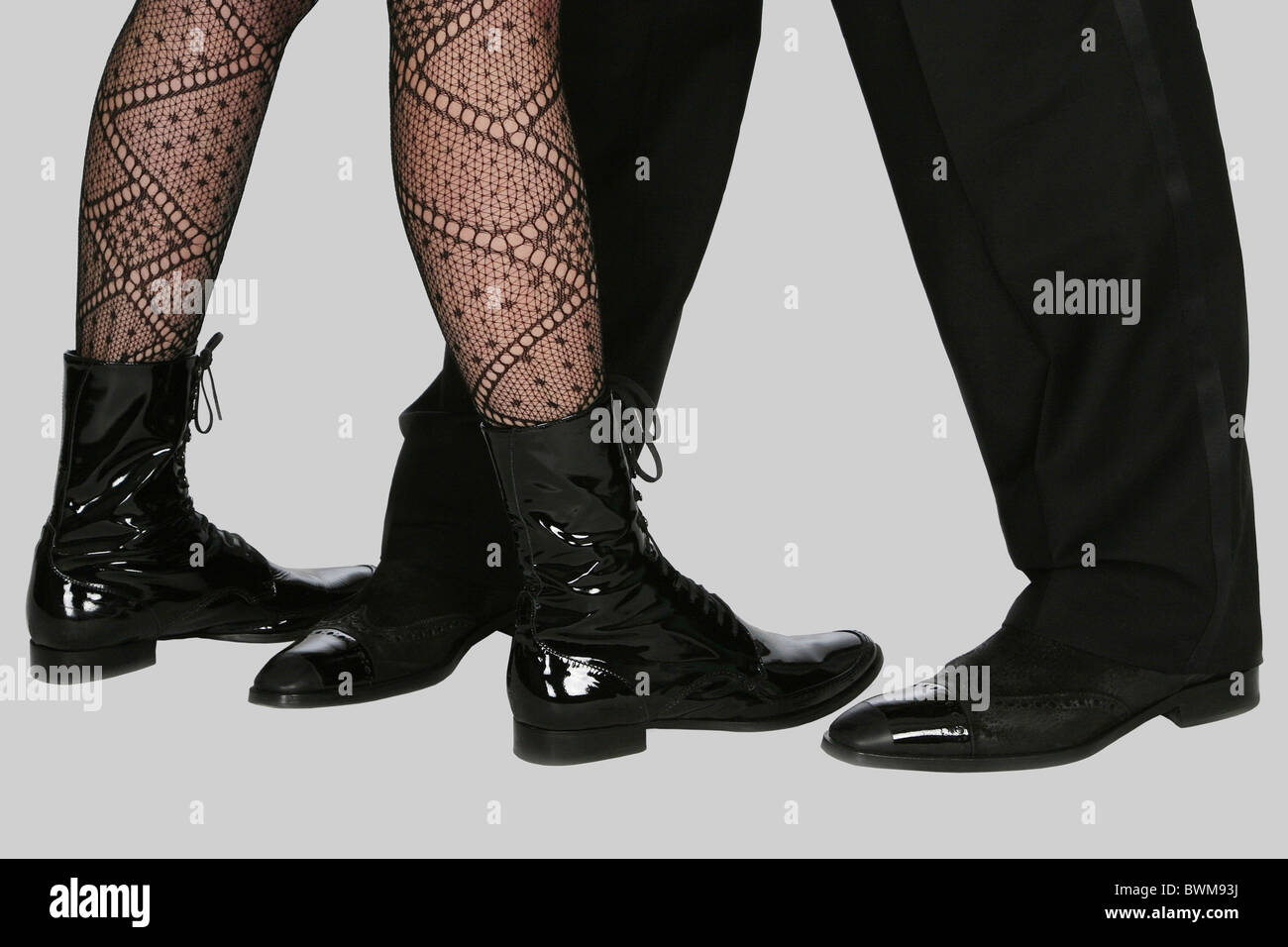 Four legs in black footwear on the grey background Stock Photo - Alamy