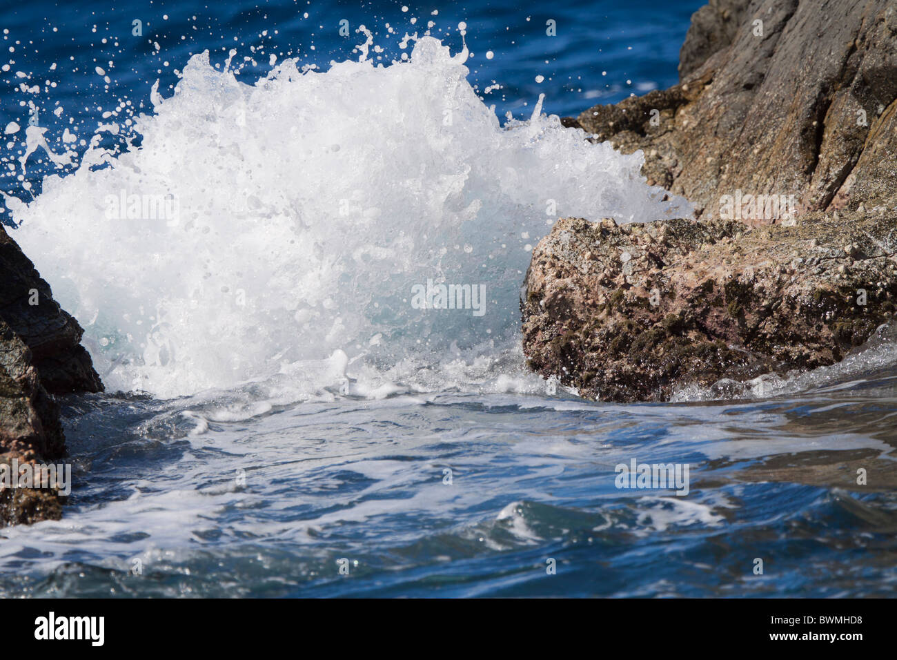 Splash. A wave splashes as it hits a narrow gap between two rocks on a ...