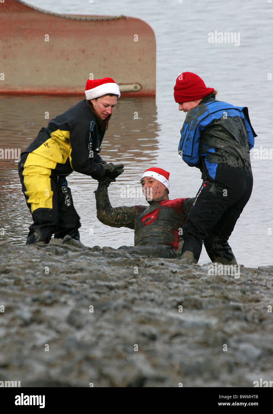 a man being helped put of the mud by two divers at the maldon mud race ...
