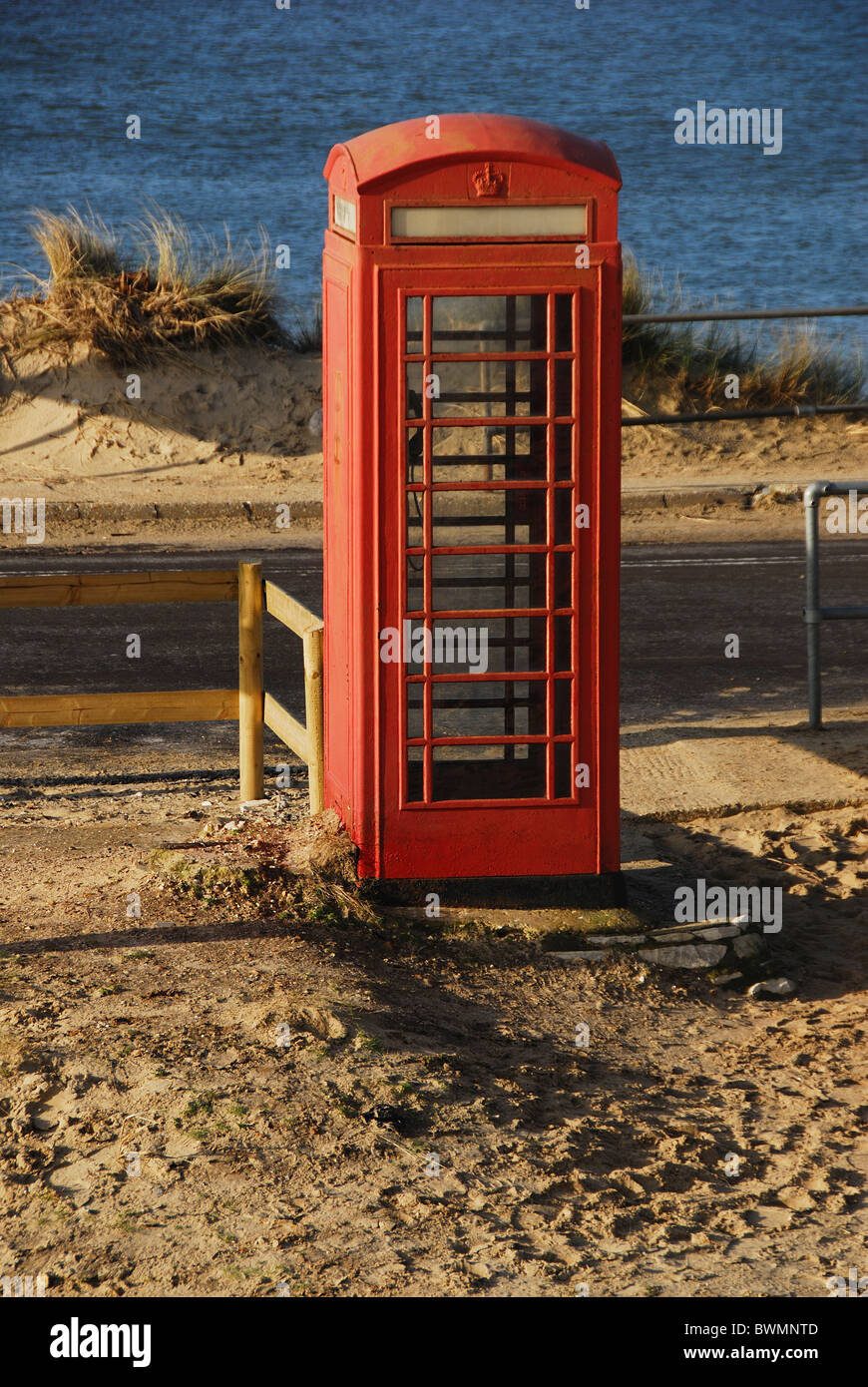 A red telephone box on the beach with the sea and the sand in the ...