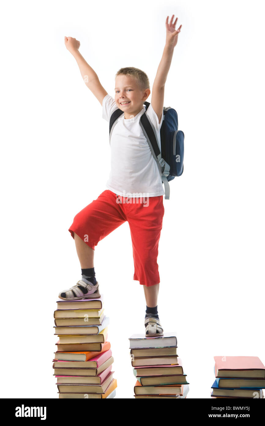 Diligent preschooler standing on the top of book stairs with his arms ...