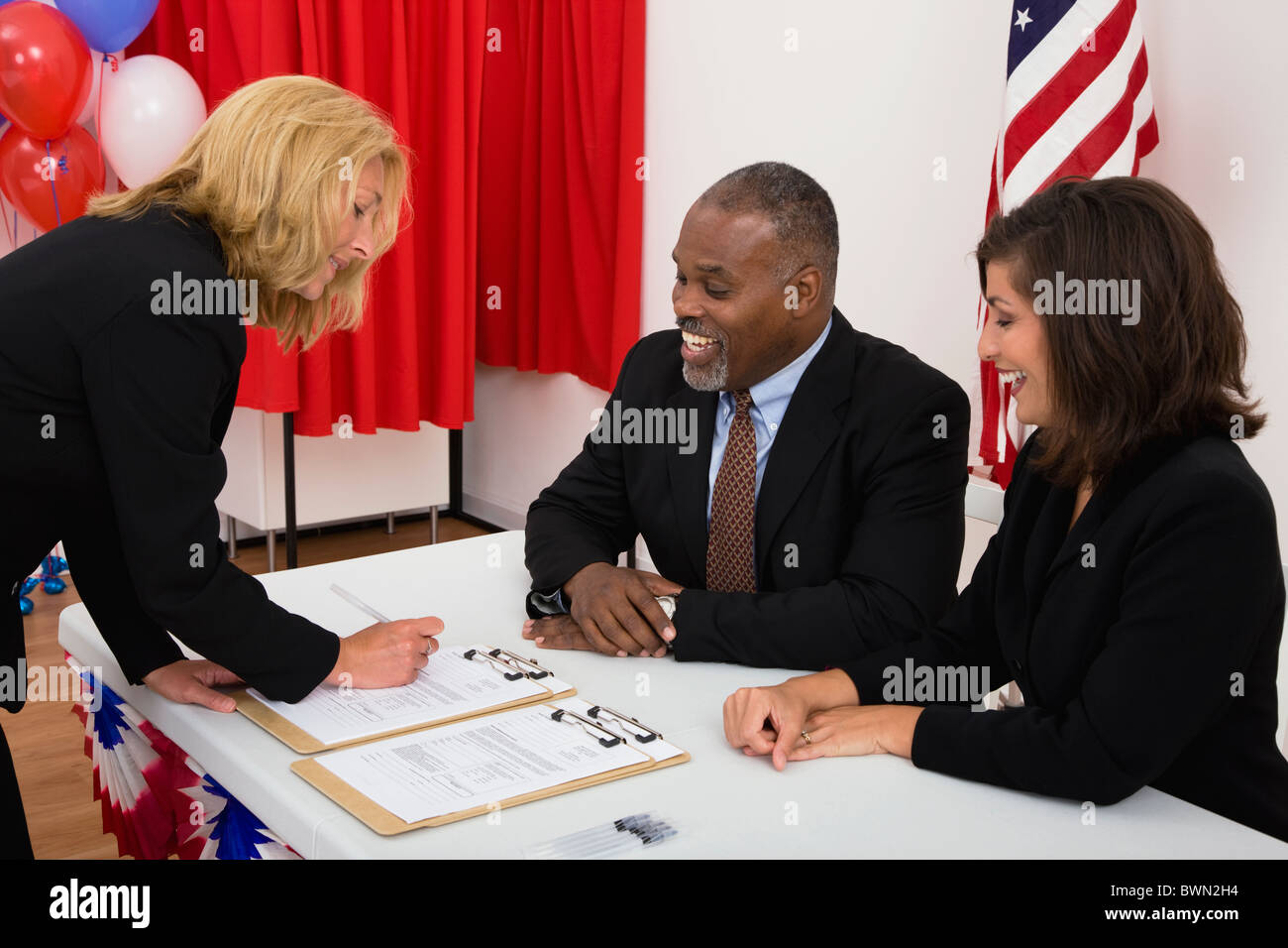USA, Illinois, Metamora, People at polling place table, US flag ...