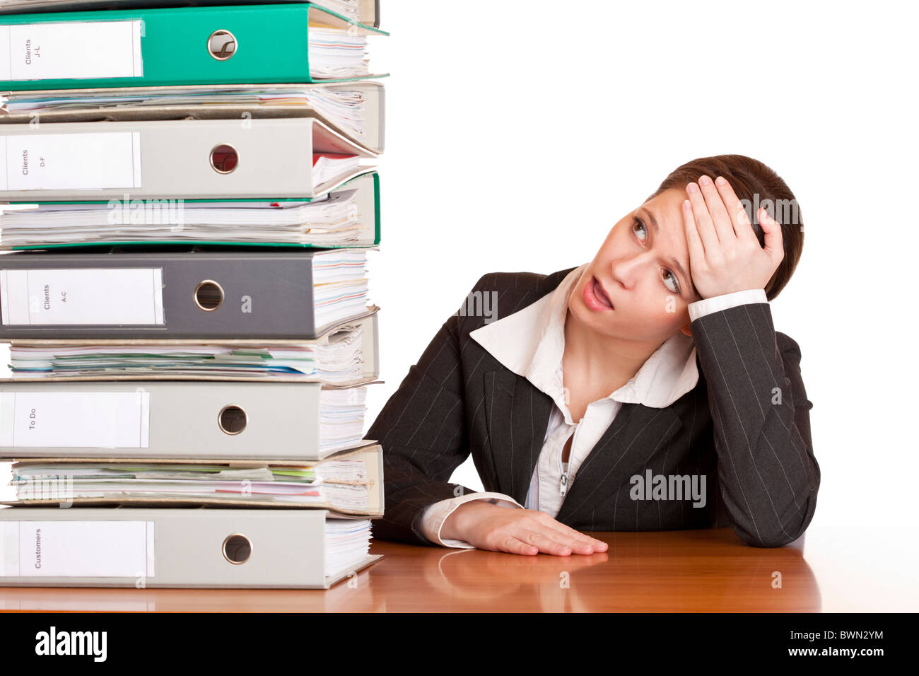 Frustrated business woman in office looks at unbelievable folder stack ...