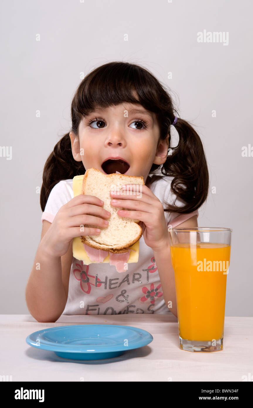 Girl eating a sandwich with a glass of orange juice Stock Photo - Alamy