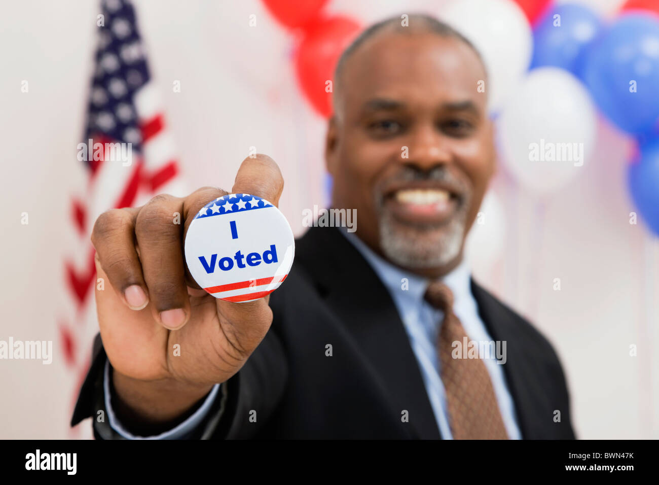 USA, Illinois, Metamora, Portrait of smiling man holding vote button ...