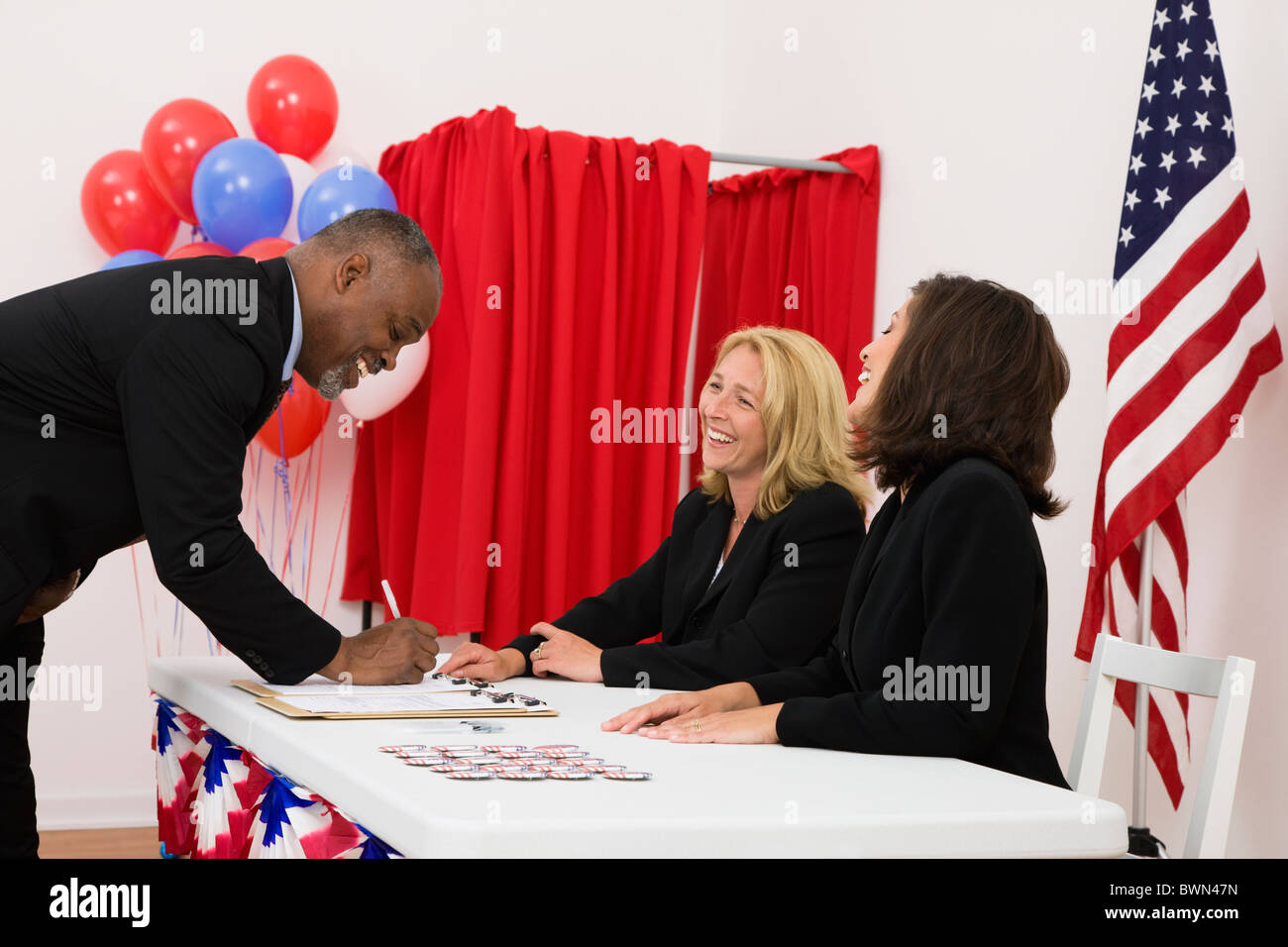 USA, Illinois, Metamora, People at polling place table, US flag ...