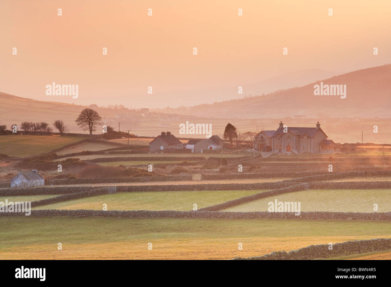 Hazy sunset over farmland near the Mourne mountains and the village of ...