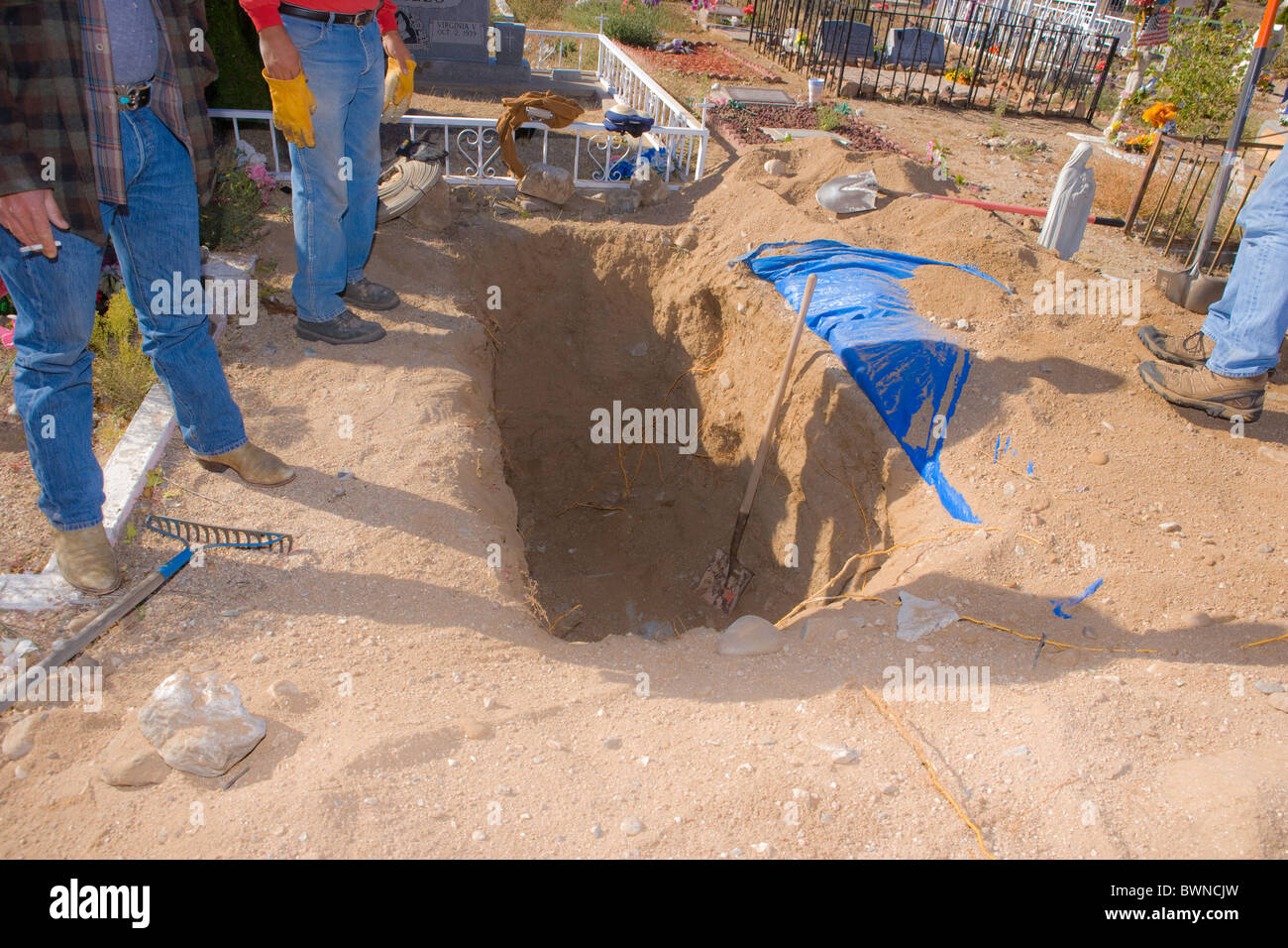 Cemetery, grave site, two people standing next to grave with shovel ...