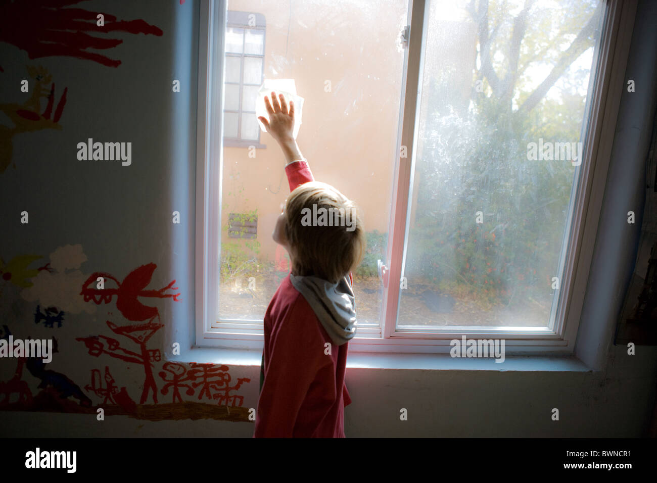 Eight year old boy cleaning his bedroom window with a paper towel Stock ...