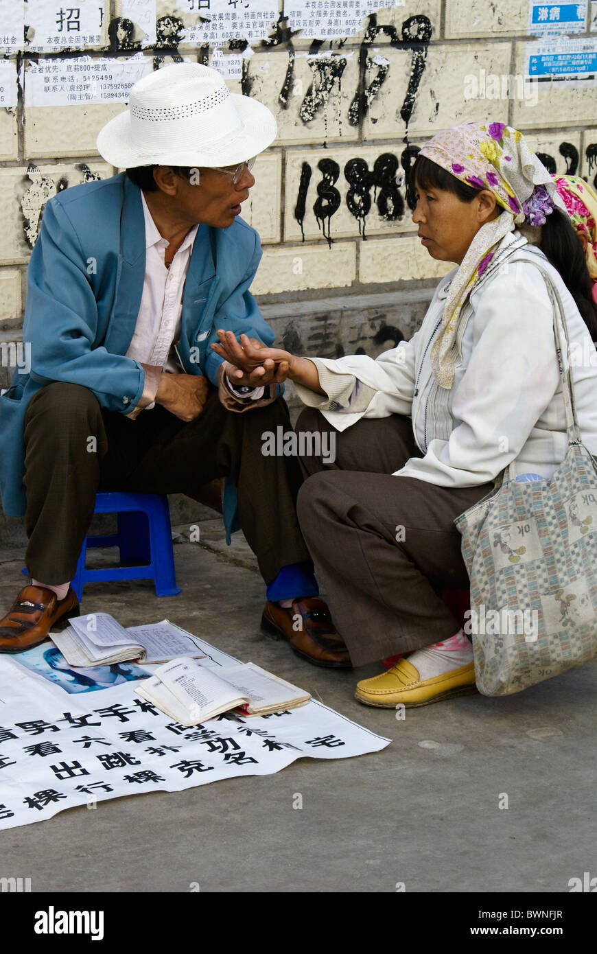 Man reading woman's palm, Menghai, Xishuangbanna, Yunnan, China Stock ...