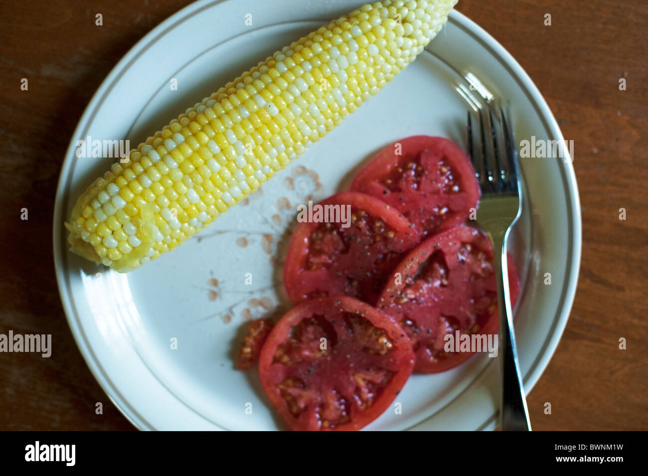 Bi-coloured sweet corn on the cob and sliced ripe tomatoes makes a ...
