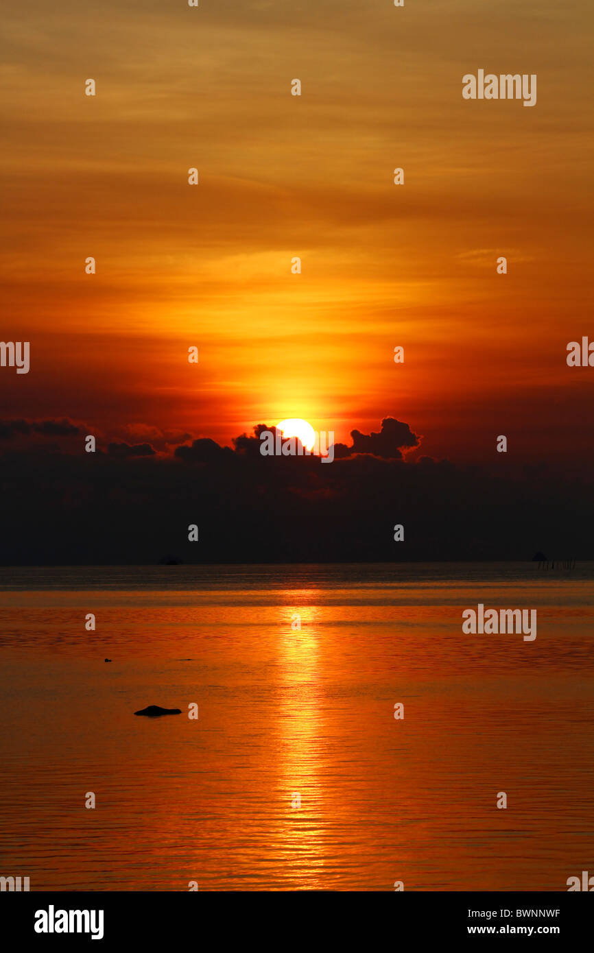 A golden sun rises behind silhouetted clouds Stock Photo - Alamy