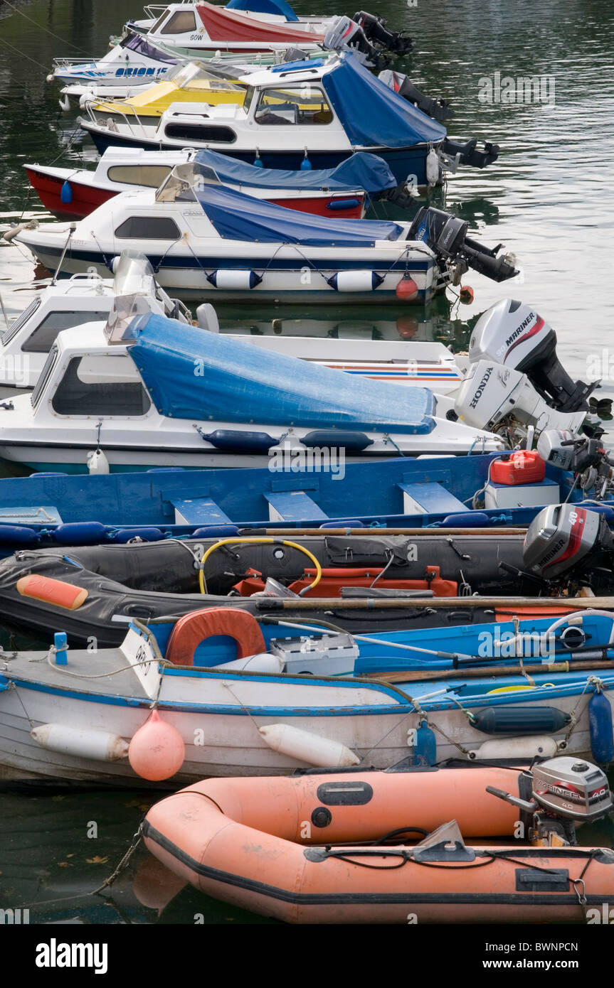 Brightly coloured boats moored in a row at Saundersfoot harbour in ...