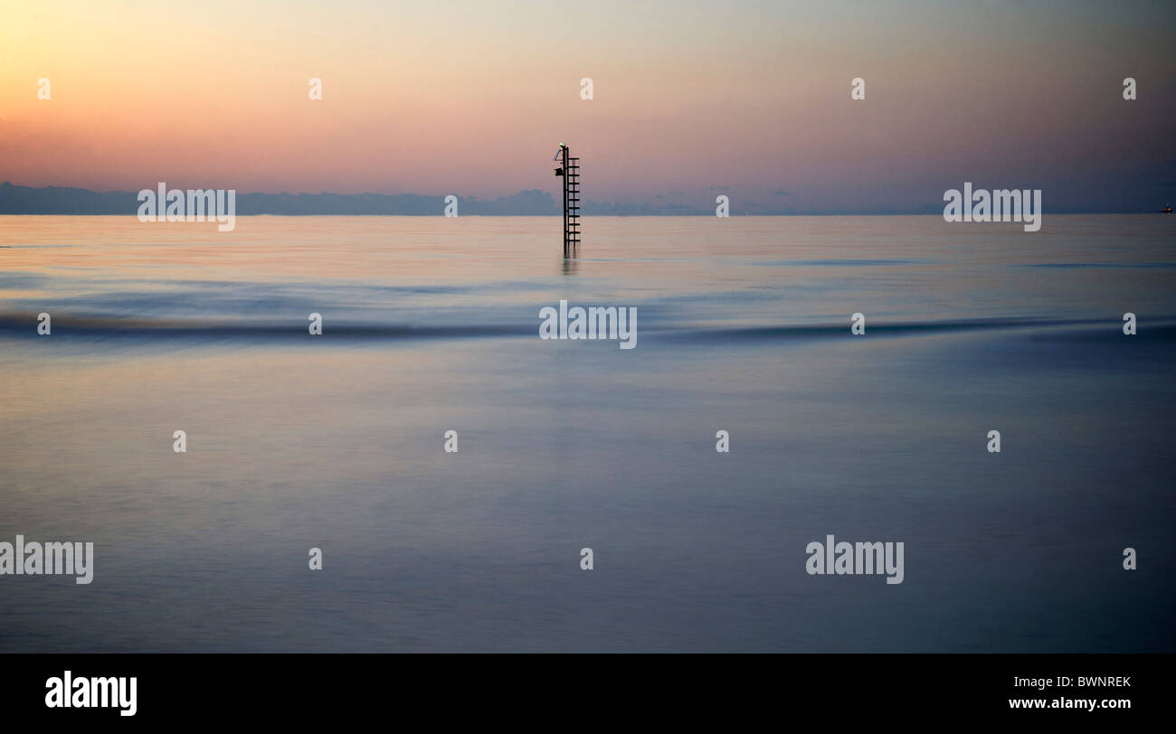 Navigation light in river estuary channel at dusk to guide ships into ...