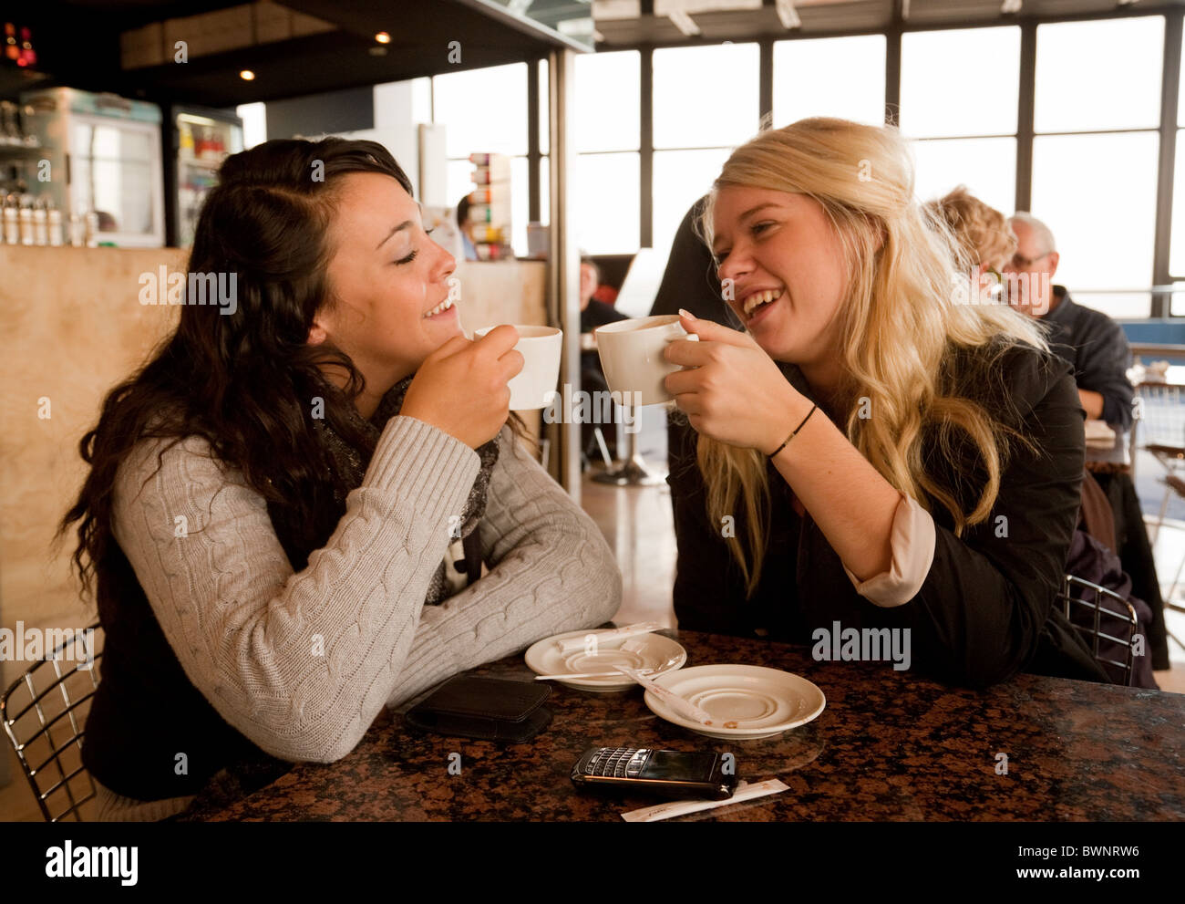 Two attractive young women drinking coffee and talking in a cafe, Paris ... Two attractive young women drinking coffee and talking in a cafe, Paris ...
