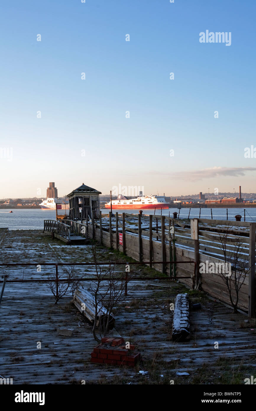 Derelict hut on jetty on the River Mersey with passenger ferry docked ...