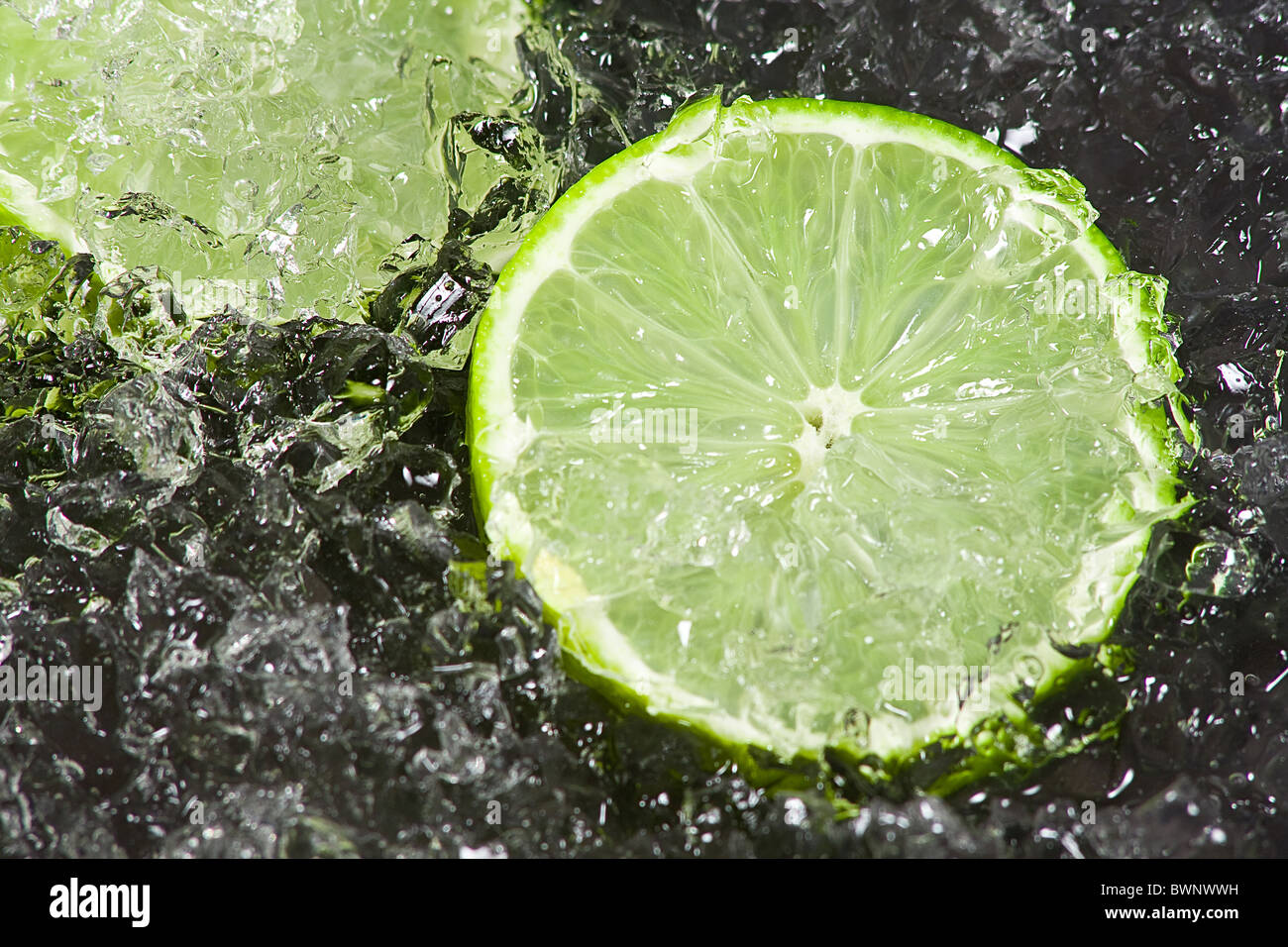 Slices lime with crushed ice on black background Stock Photo - Alamy