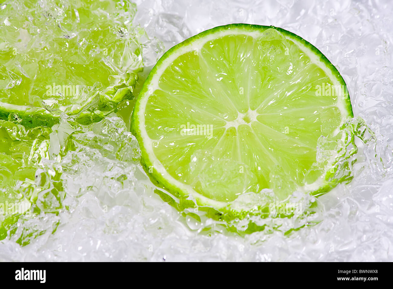 Slices lime with crushed ice on white background Stock Photo - Alamy